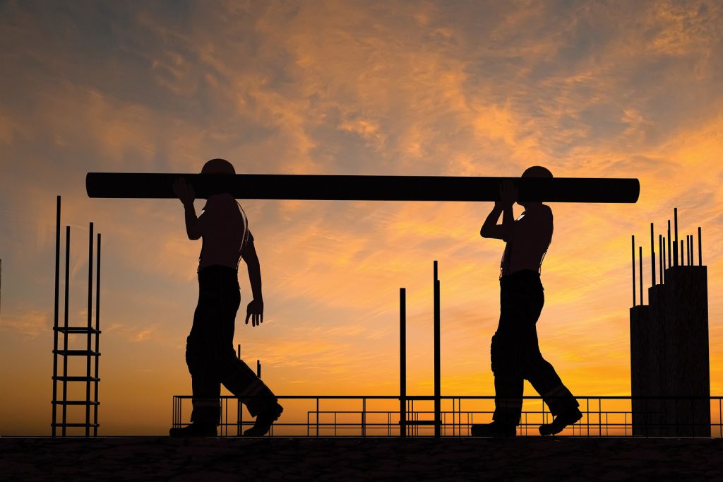 bigstock-Two-workers-carry-a-pipe-47262031 - Construction Canada